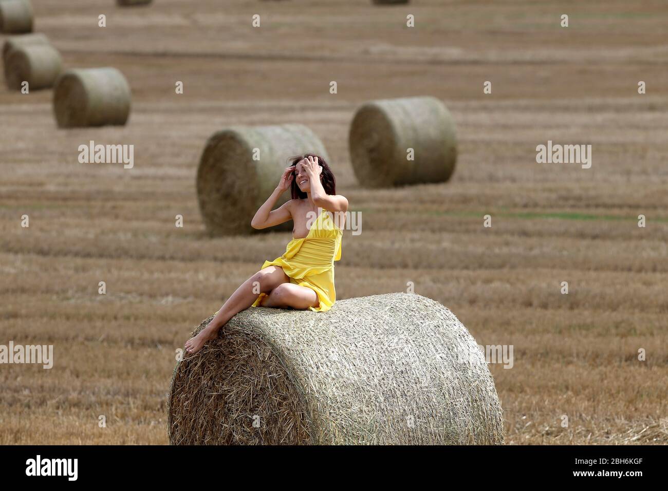 A young beautiful woman in a yellow dress with a roll of hay Stock ...