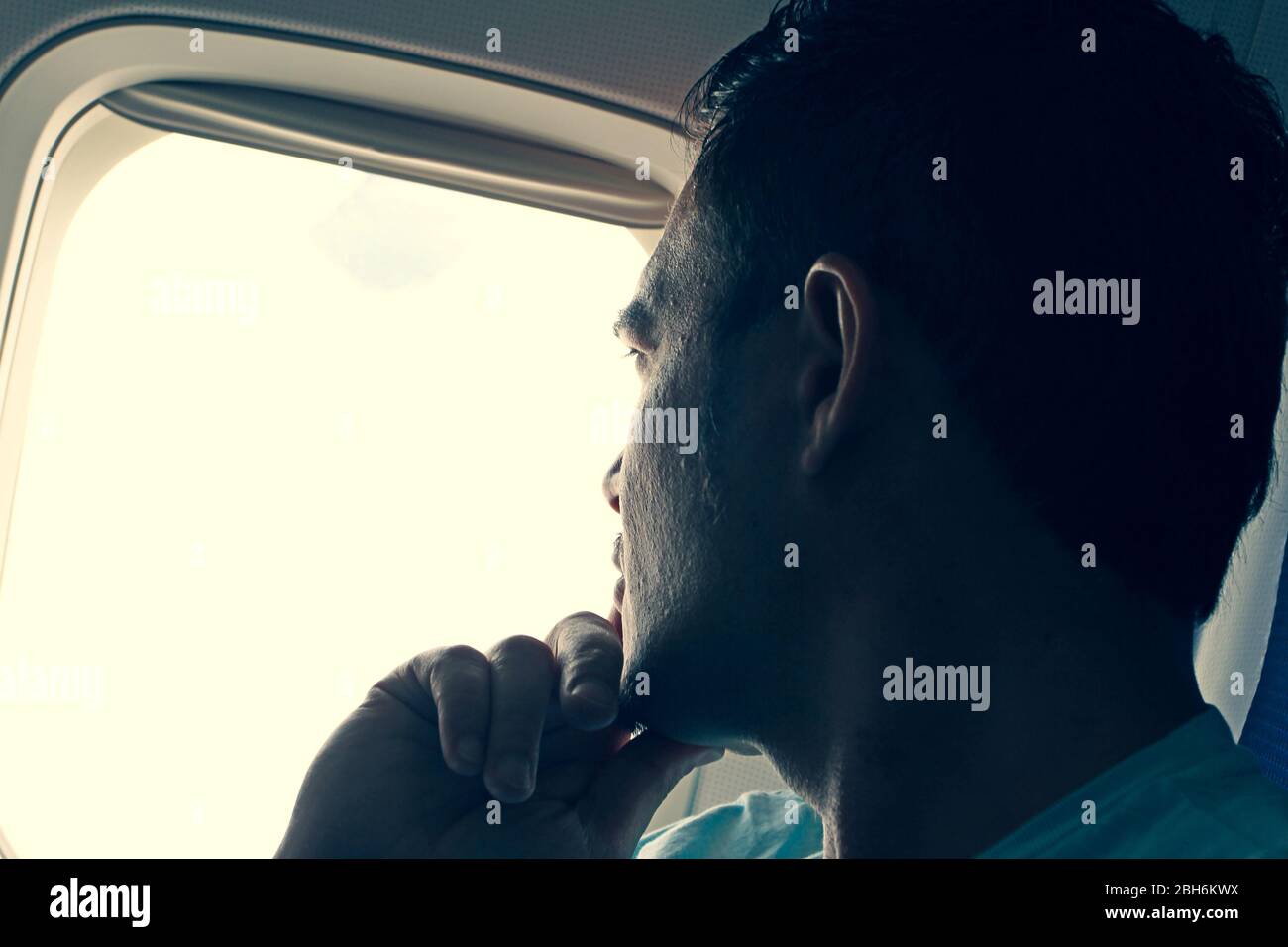 Young passenger looking out through window of the flying airplane. Side ...