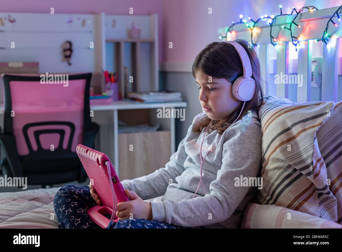 Cute little girl using tablet while lying in bed Stock Photo - Alamy