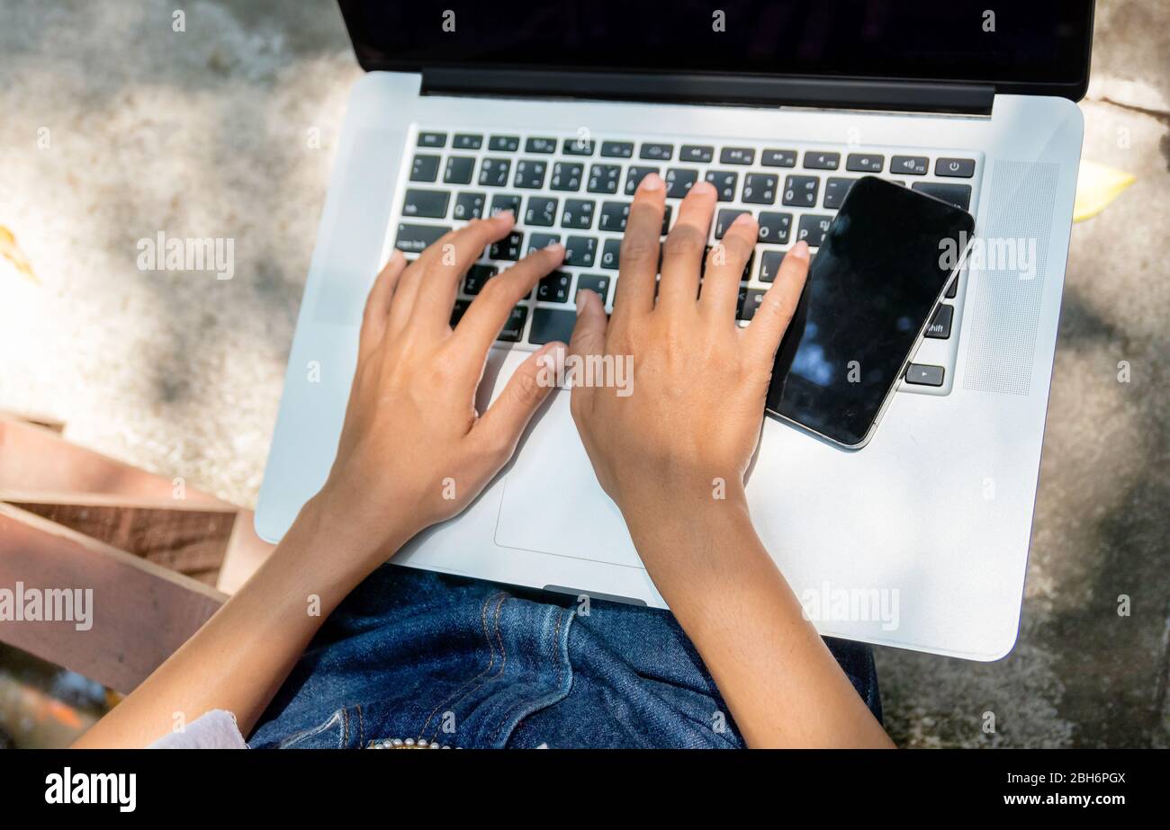 Two hands typing on keyboard with a mobile phone Stock Photo - Alamy