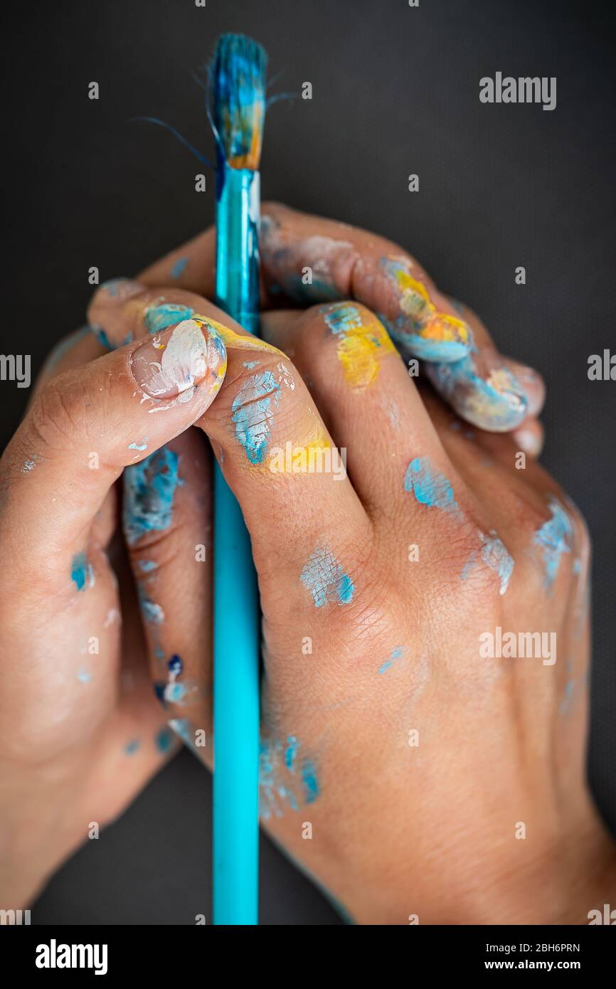 Human hands with paintbrush, stained with paint, artist’s creative ...