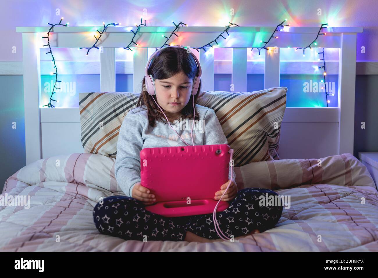 Cute little girl using tablet while lying in bed Stock Photo - Alamy