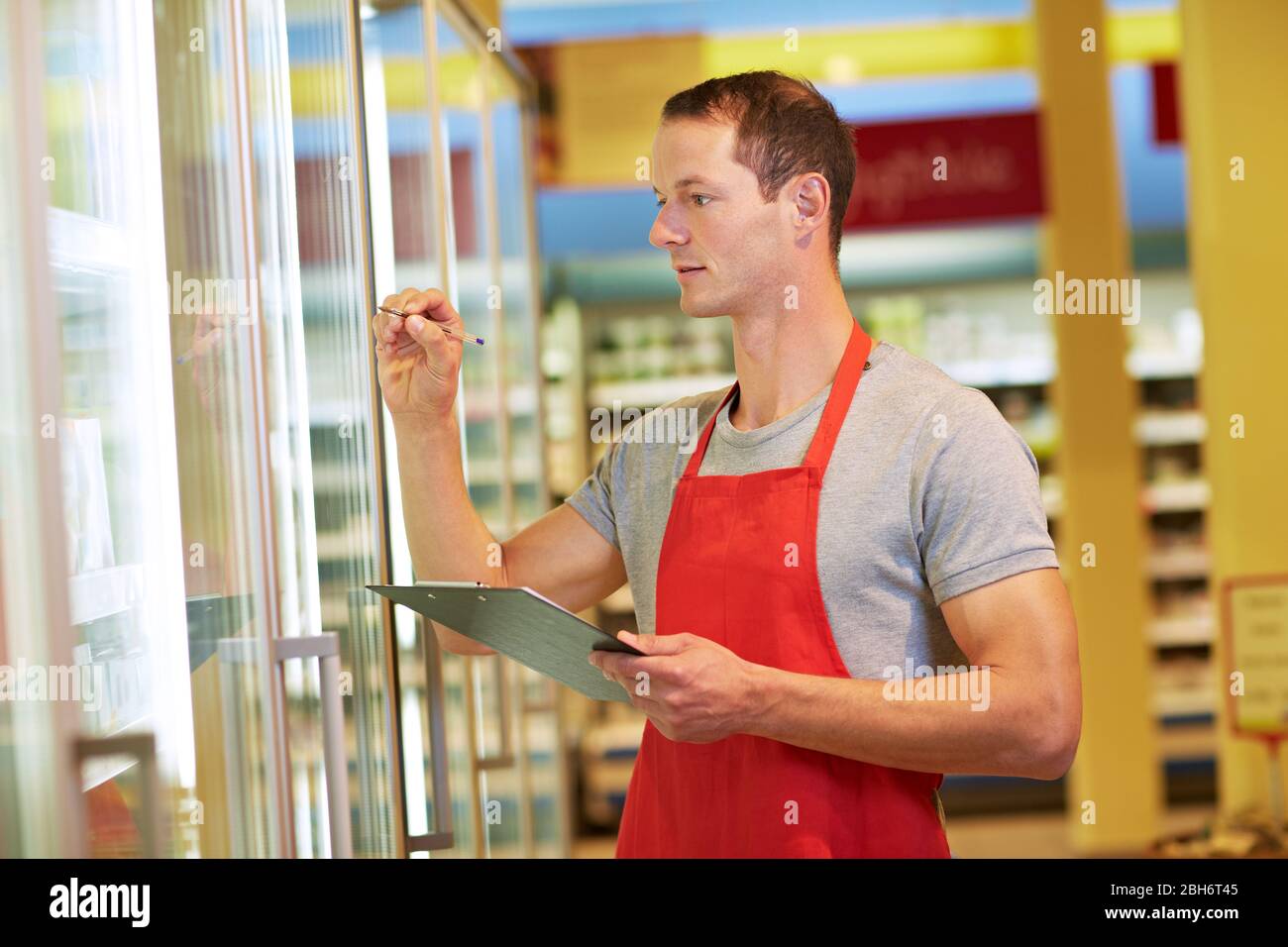 Employee checks inventory in the refrigerated section of the ...