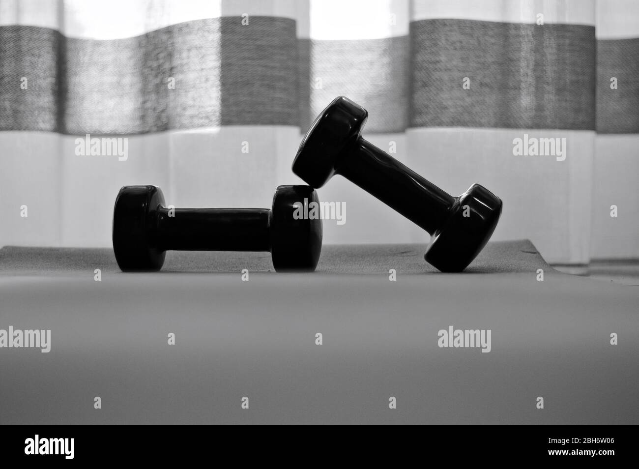 Gym workout at home with two small dumbbell weights and a gym mat ...