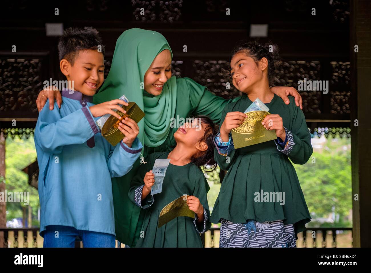 Happy and excited children holding an envelope of pocket money or raya ...
