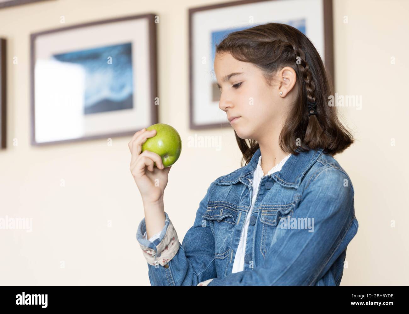 Little girl at home looking at a green apple that she doesn't want to ...
