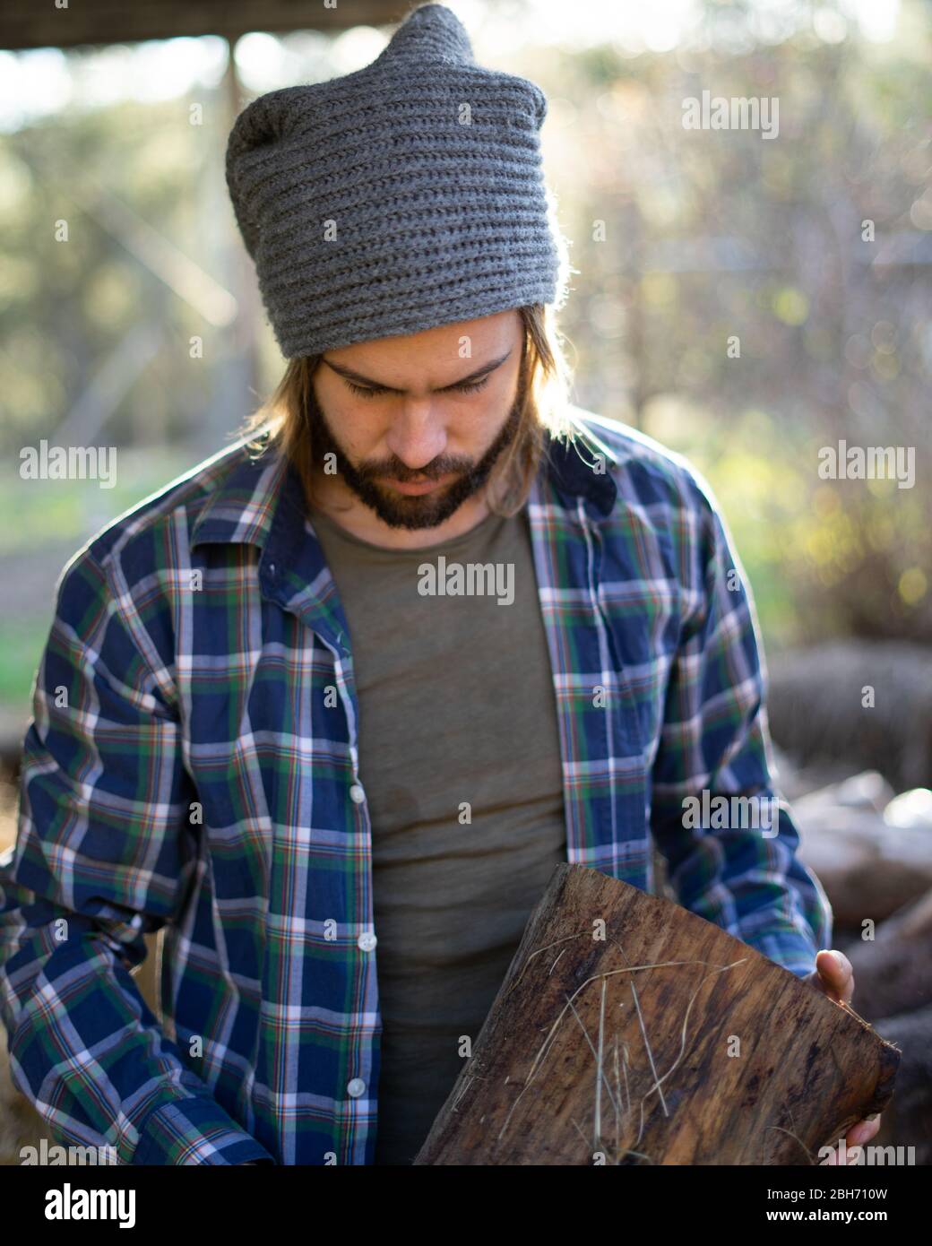 Portrait of young bearded man taking a log of wood with beautiful ...