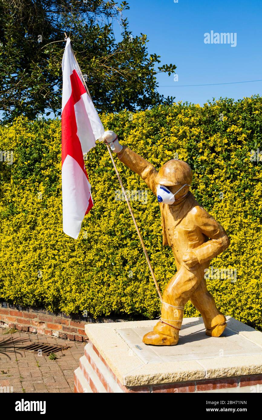 Carved, wooden “Clockpelters” statue wearing medical mask during the ...