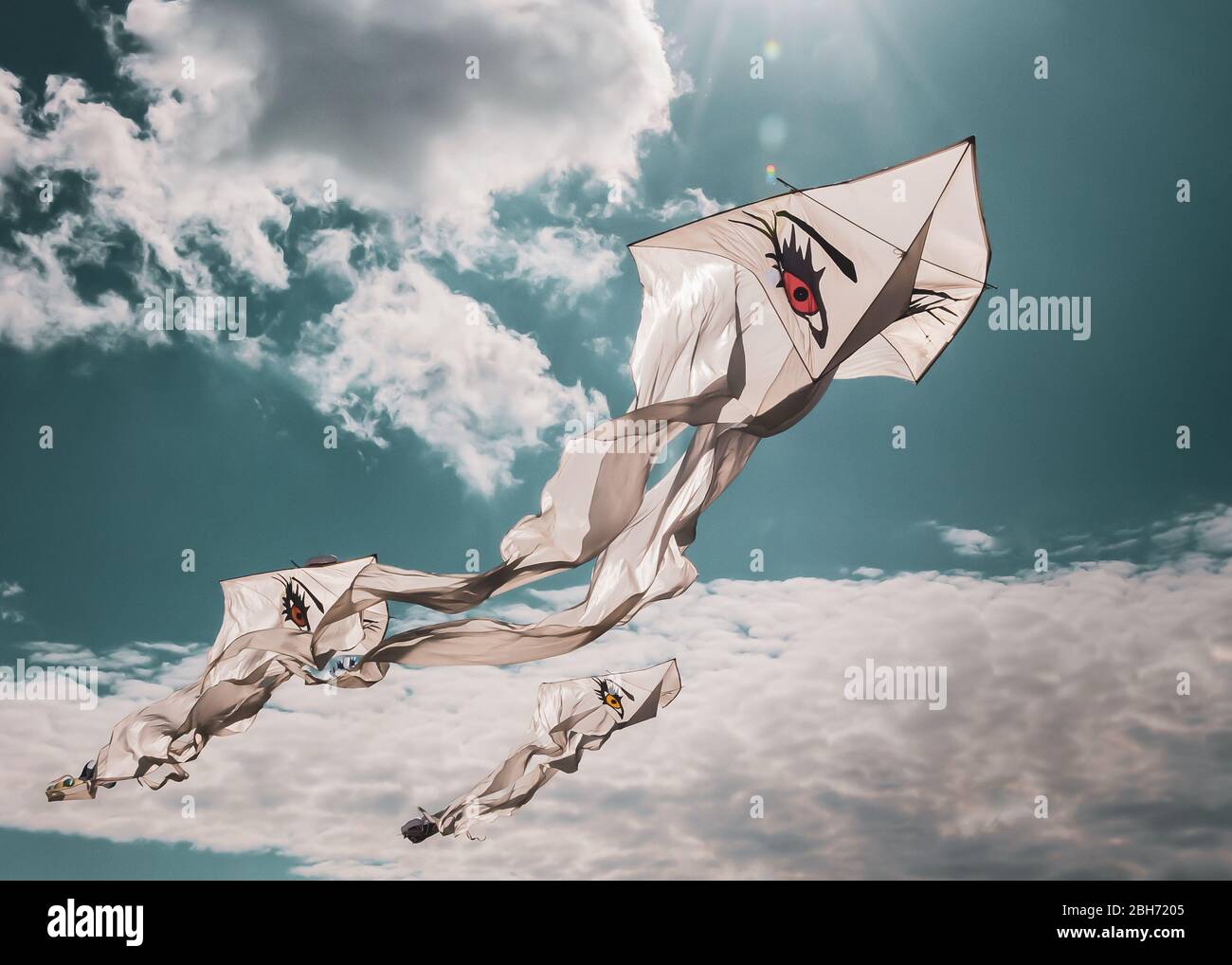 White kites with eyes flying high in the wind against a dramatic sky of ...