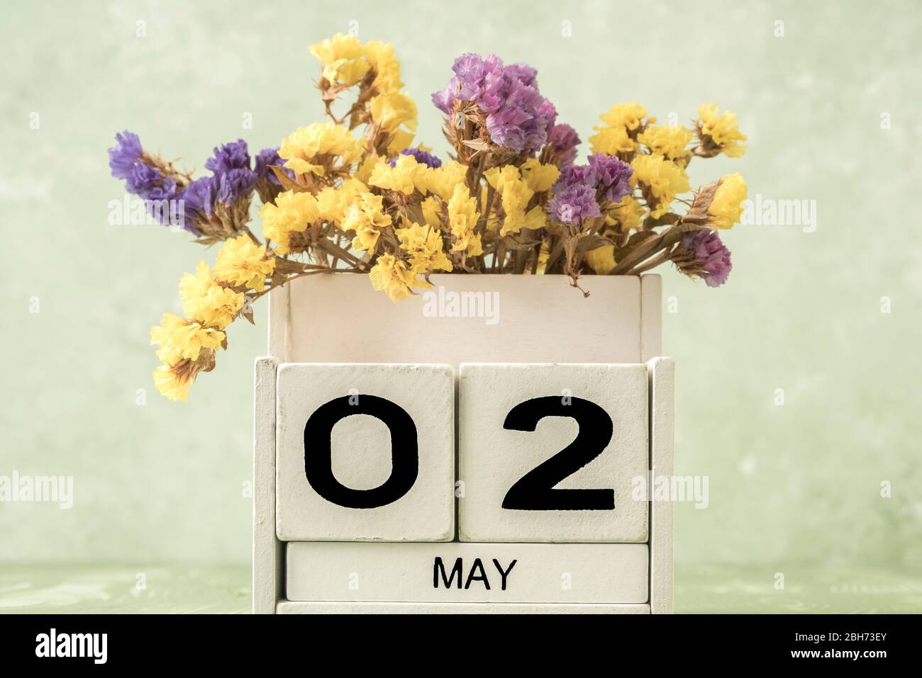 White cube calendar for may decorated with flowers over green ...