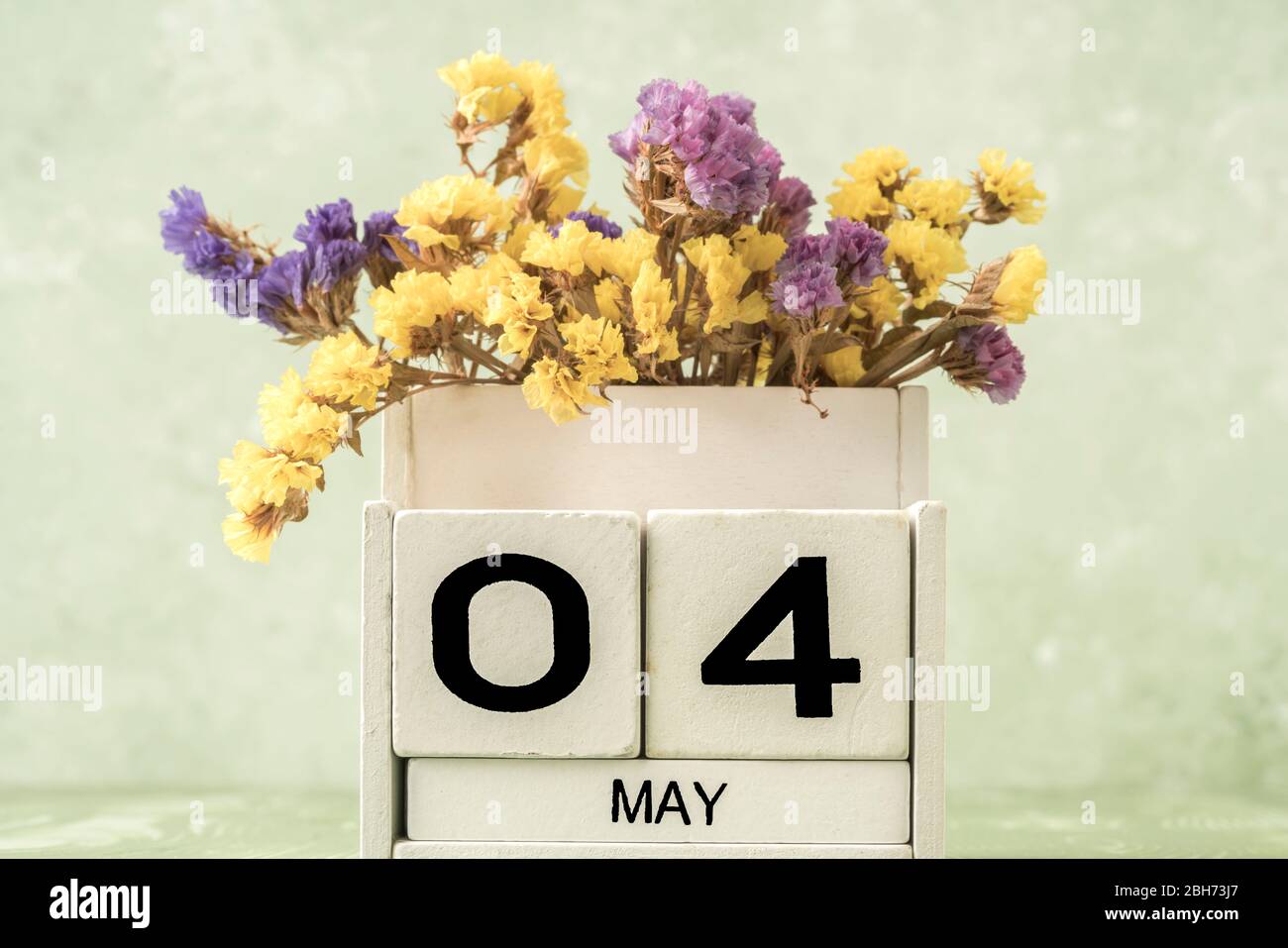 White cube calendar for may decorated with flowers over green ...