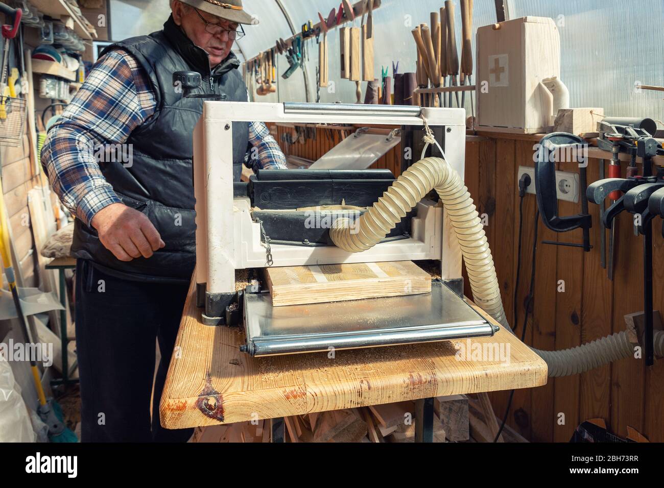 Senior craftsman woodworking at carpentry with lots of modern ...