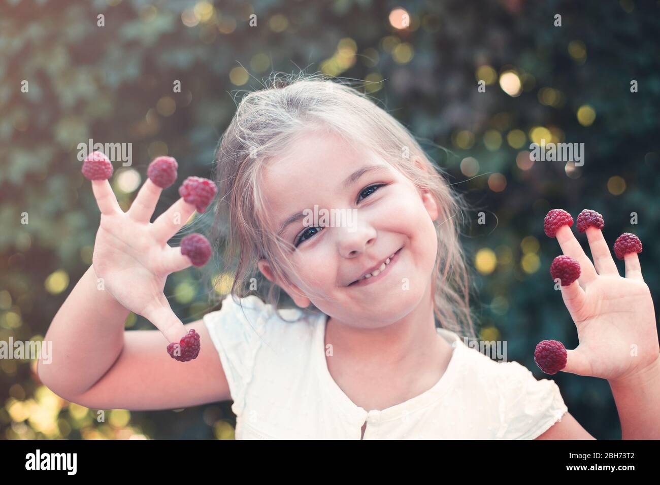 Happy little child with raspberry on her fingers outdoors Stock Photo ...