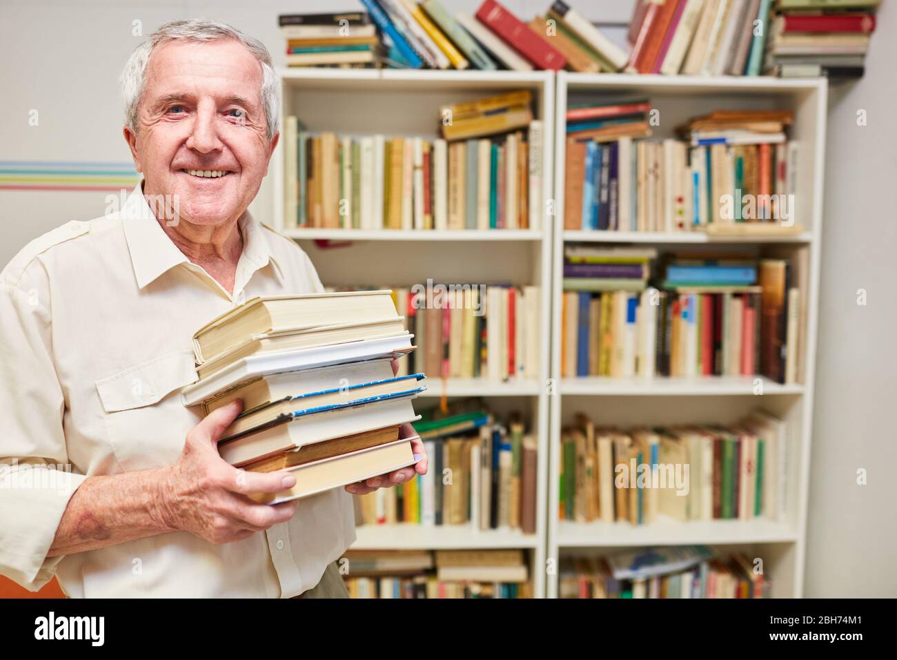 Satisfied senior librarian with a pile of books in a library Stock ...