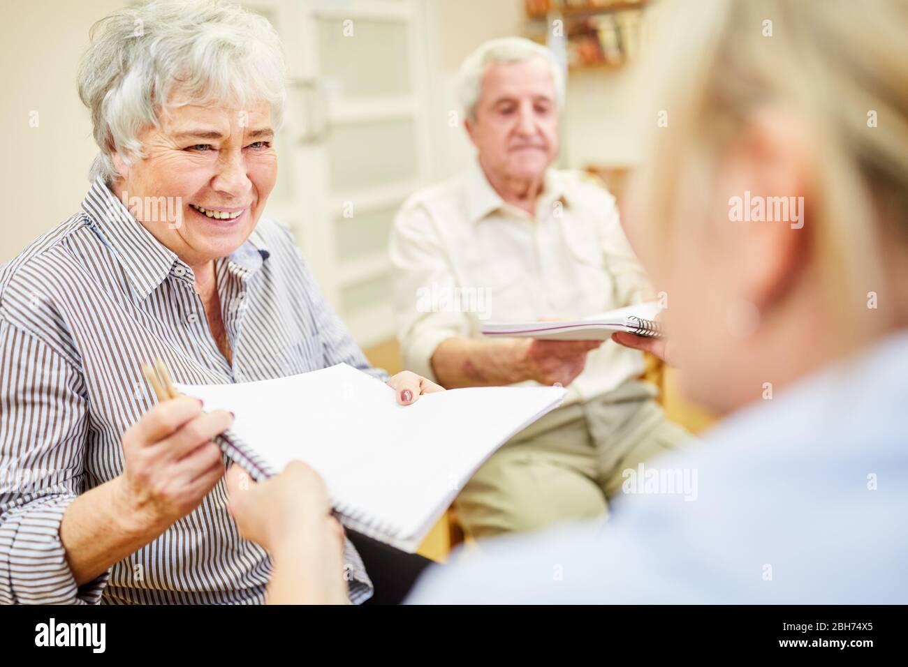 Cheerful senior woman and therapist in creative painting therapy with ...