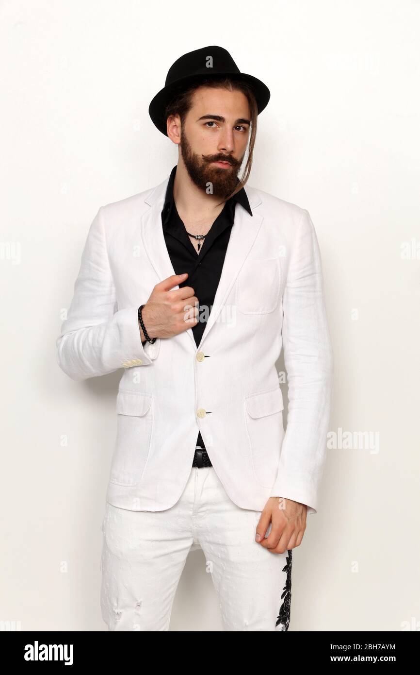 Young, fashionable male model with long hair and beard posing in studio ...