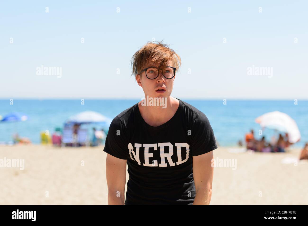 Stressed young nerd man looking bored and tired at the beach Stock ...