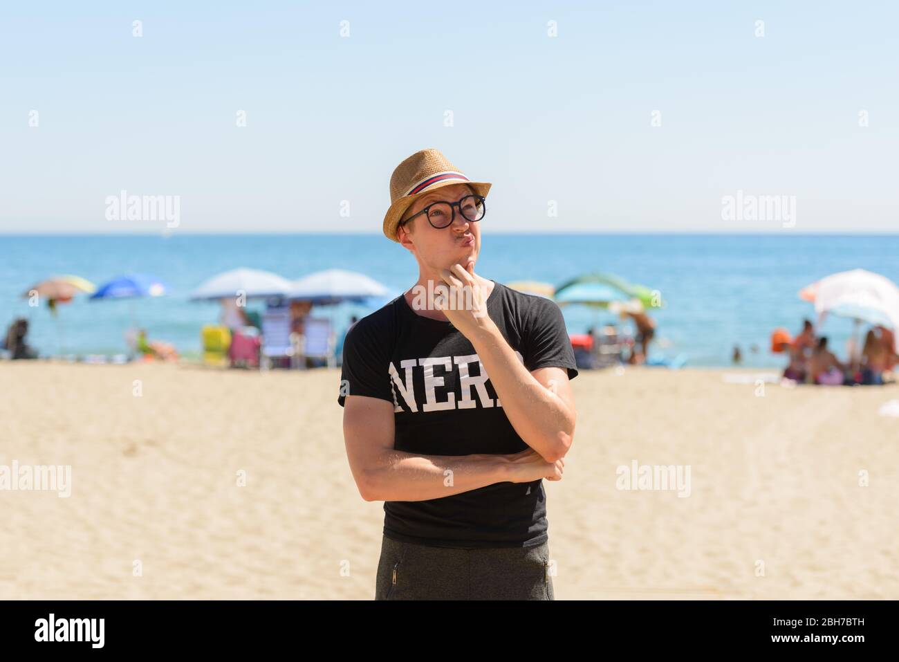 Young nerd tourist man thinking at the beach Stock Photo - Alamy