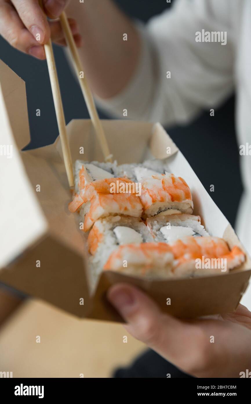 man eating roll philadelphia with shrimps chopsticks from craft box ...