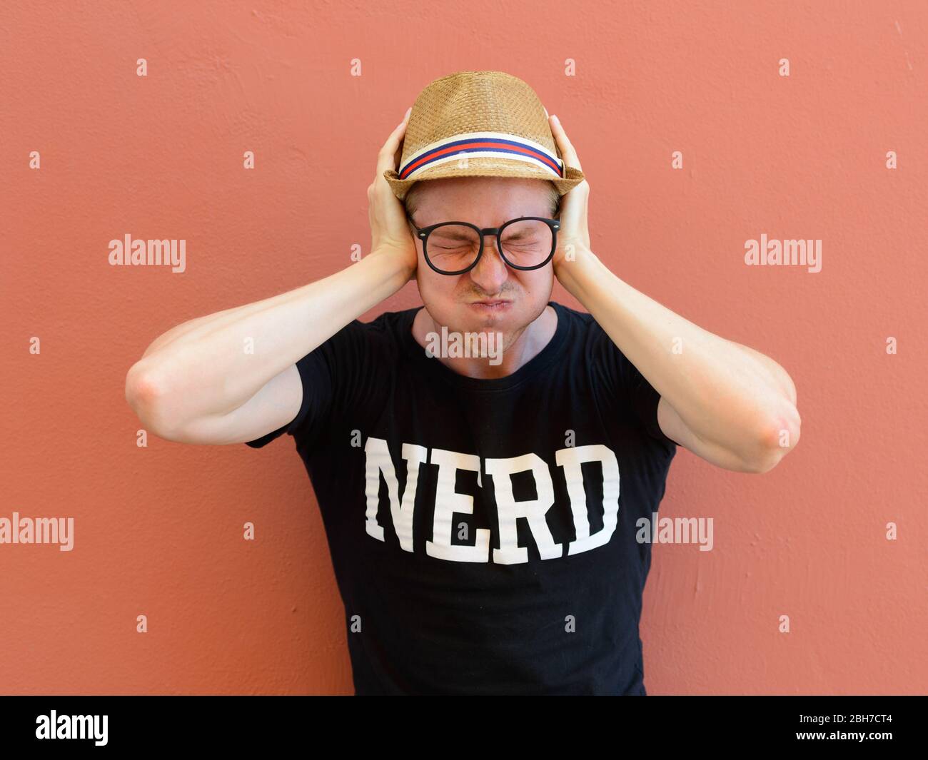 Portrait of stressed young nerd tourist man covering ears Stock Photo ...