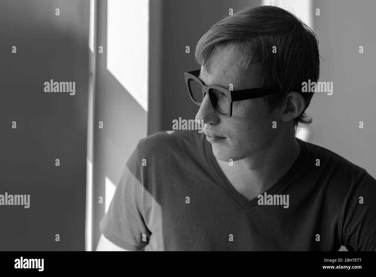 Closeup profile view of nerd man looking out the window in black and ...