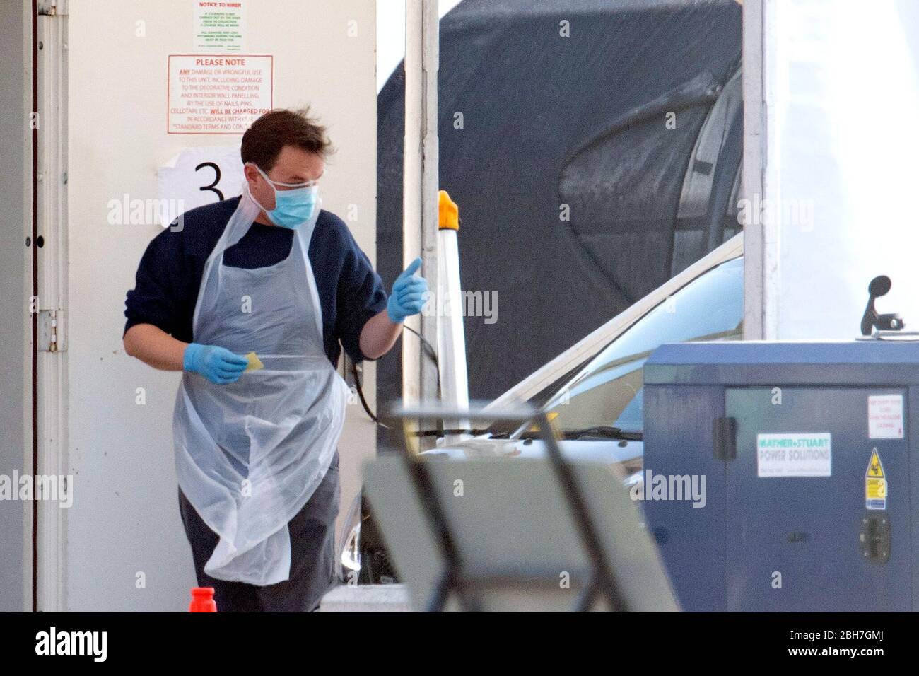 Testers wearing personal protective equipment (PPE) at work at a drive ...