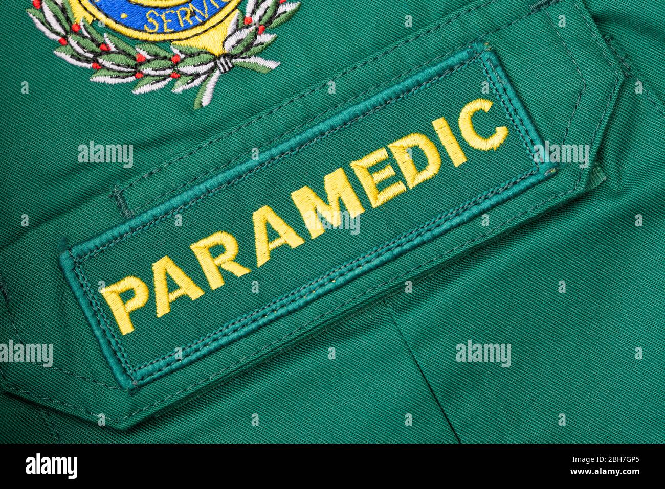 Close up, angled view of a British PARAMEDIC badge sewn onto green ...