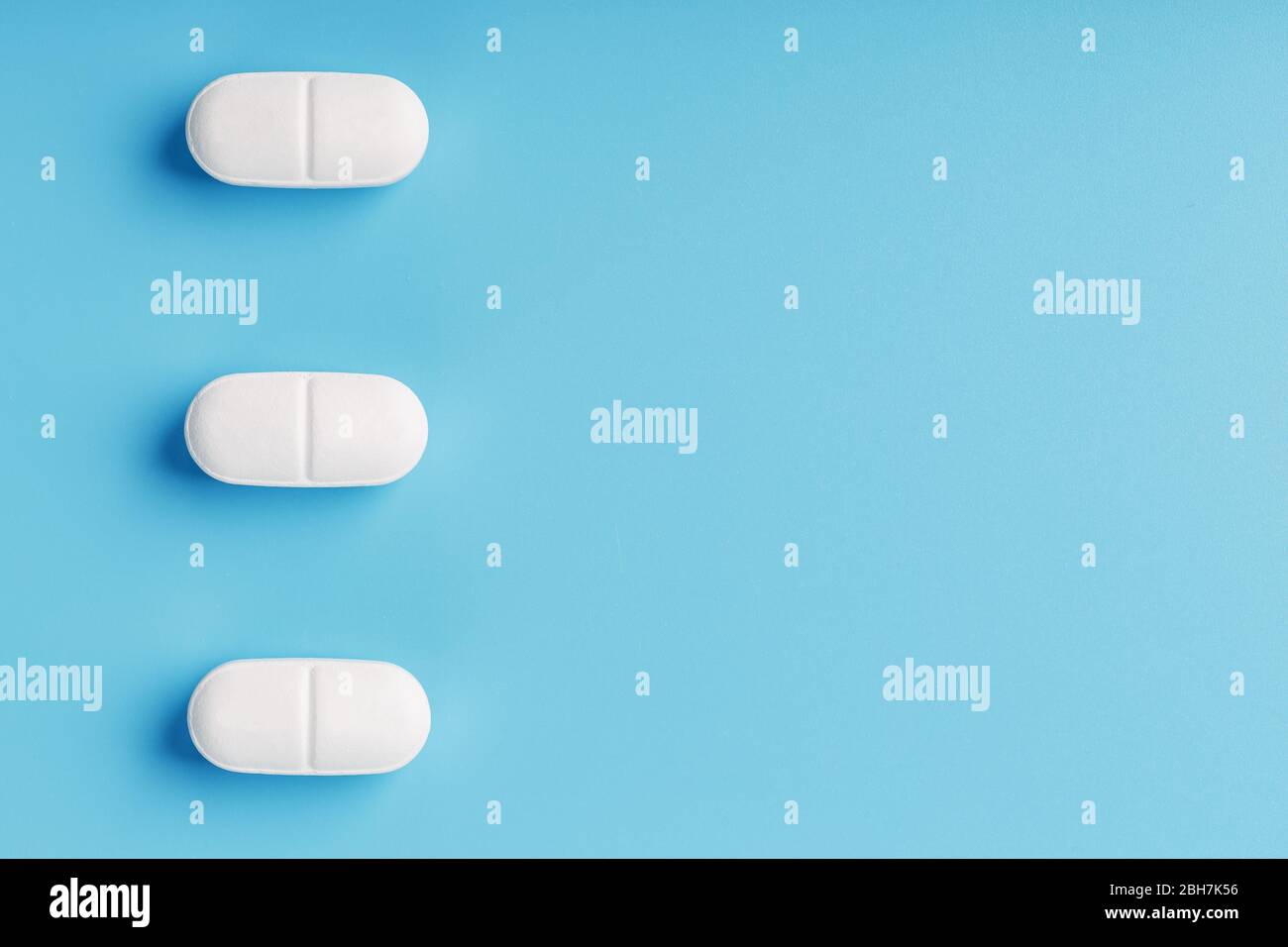 Three medicinal tablets in a row on a blue background, isolate Stock ...