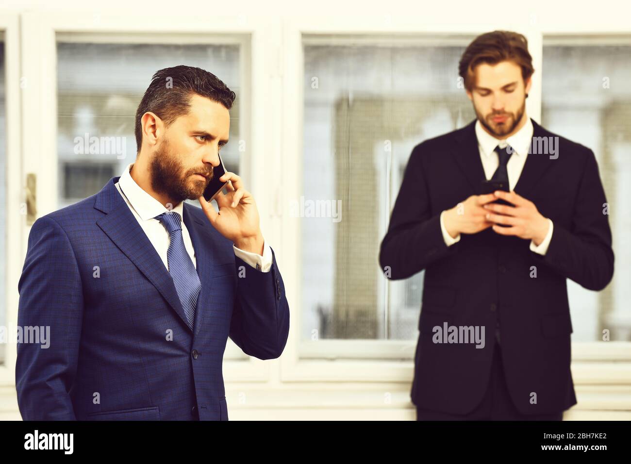 communication and technology, serious men or businessmen speaking on mobile or cell phone near ...