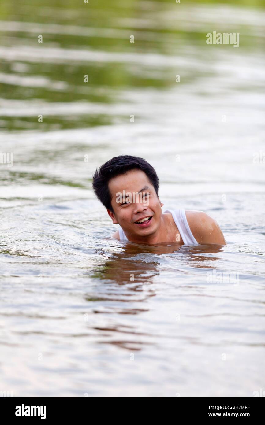 A Thai man in white tank top swimming in river Stock Photo - Alamy