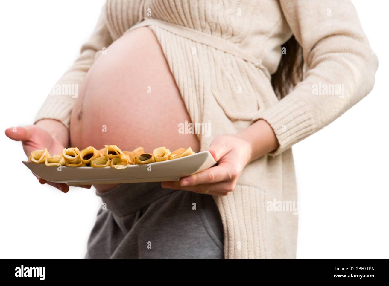 Close-up of future mom standing in profile holding pancakes plate ...