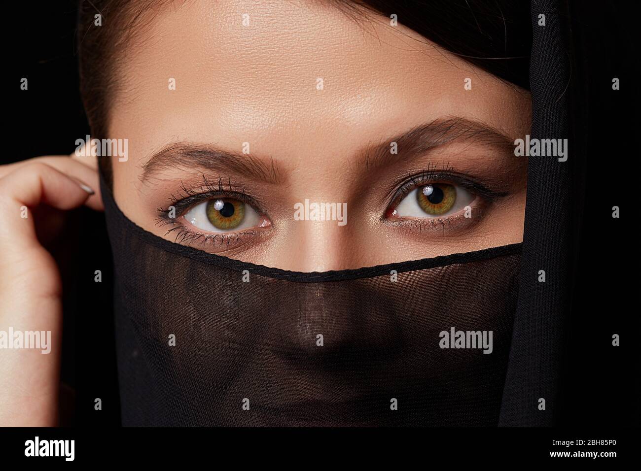 a young brown-haired woman in black clothes with her head covered and ...