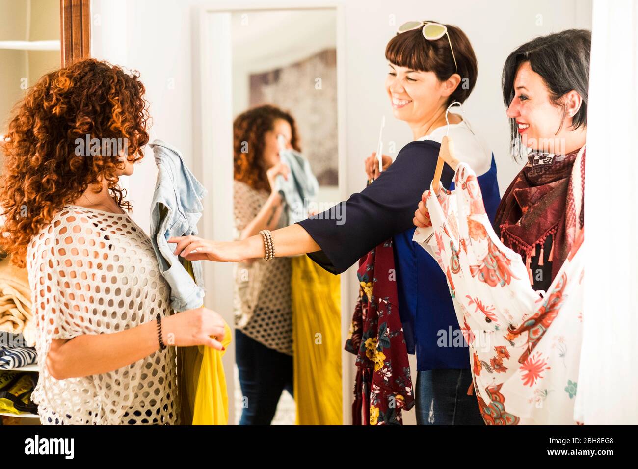 group of three caucasian friends choosing the right dress to go out for ...