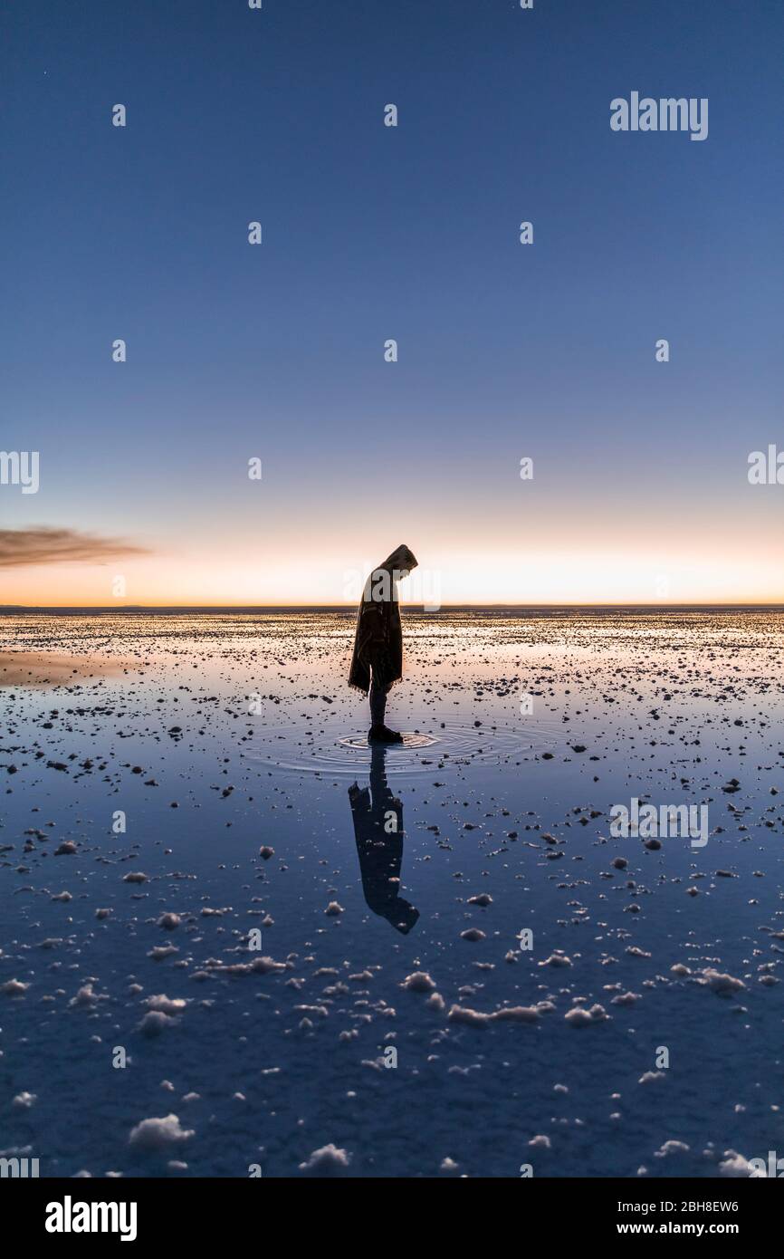 Man standing on its own reflection on water in salt flats Stock Photo ...
