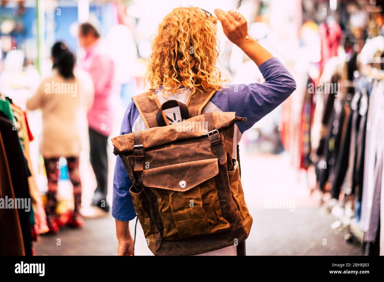 Blonde curly hair woman backpacker traveler viewed from rear at used ...