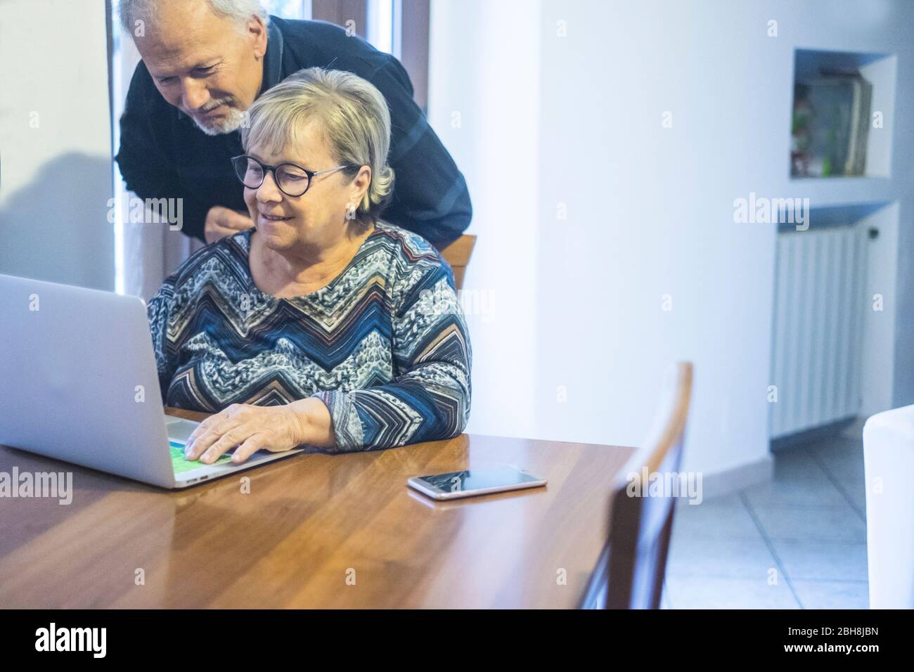 Adult senior couple at home use internet with laptop computer together ...