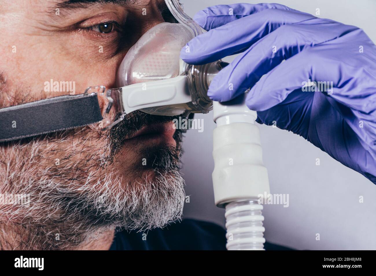 Hand with medical glove putting on a man a respiratory mask for sleep ...