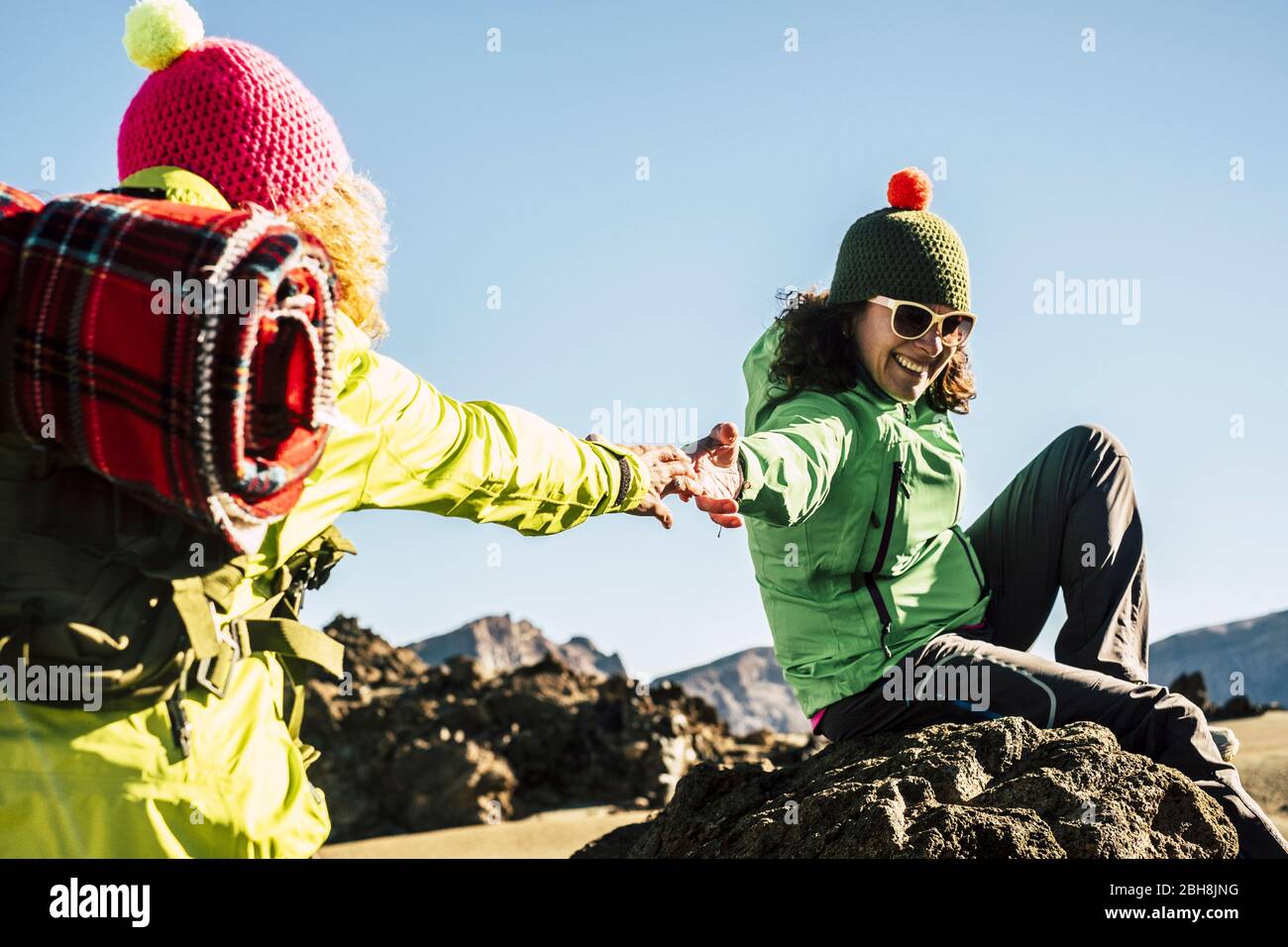 Couple of happy woman helping eachother to arrive to the top of the ...