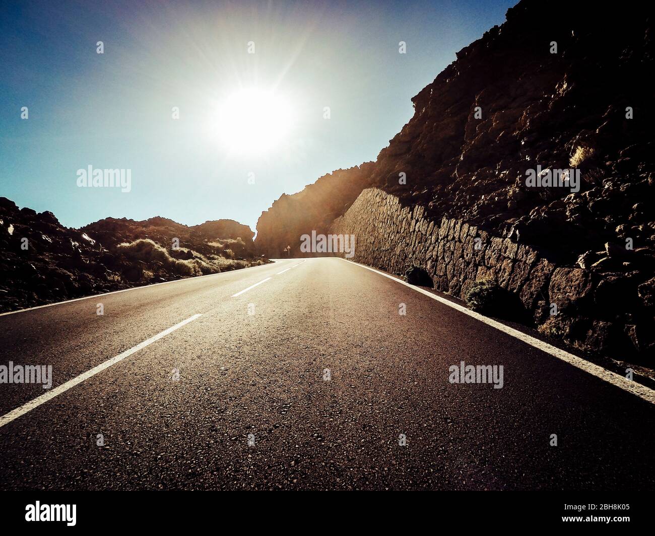 Long way road at the mountain with sun in front and sunlight effect ...