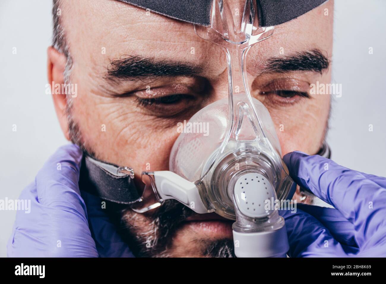 Hand with medical glove putting on a man a respiratory mask for sleep ...