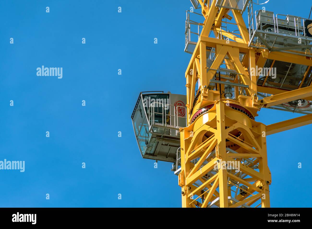 The operator cabin on a yellow tower crane with a clear blue sky ...