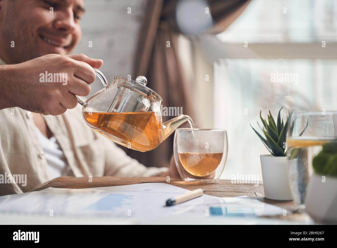 Man filling a mug with a herbal drink Stock Photo - Alamy
