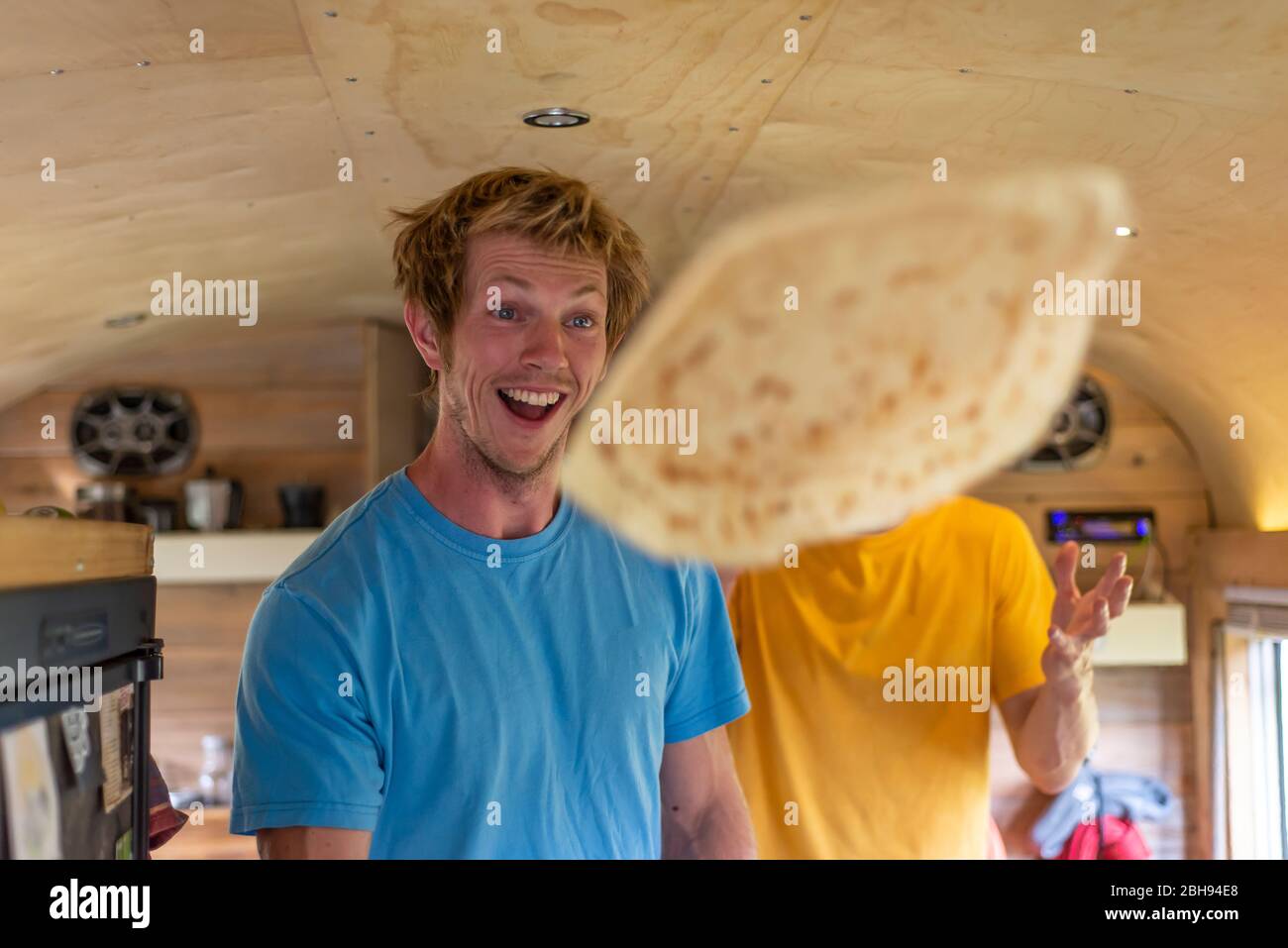 Two people making funny face while flipping crepes inside school bus ...