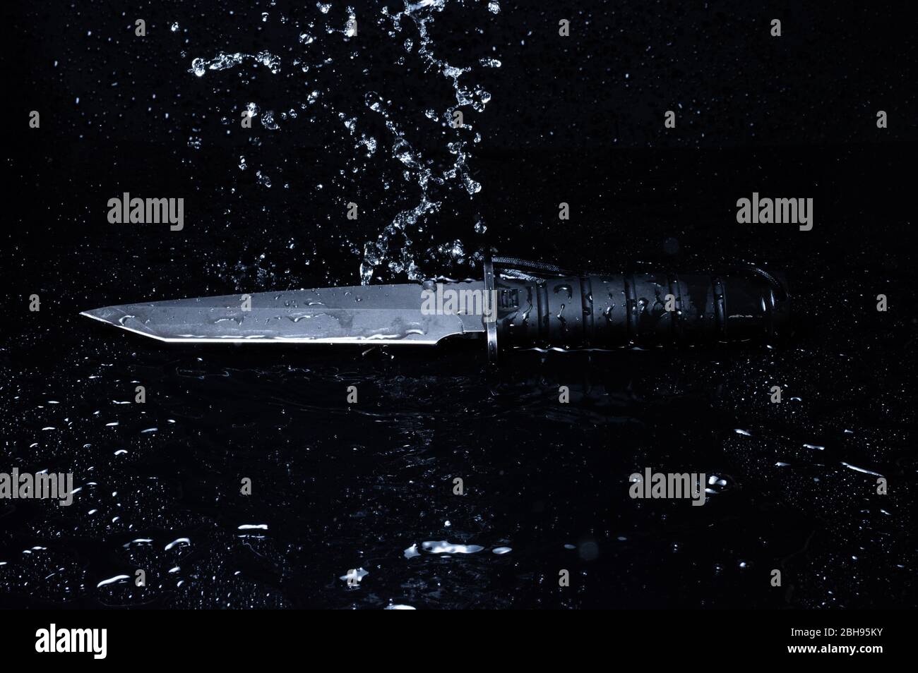 Splashes of water pour on the knife. A knife under the pressure of ...