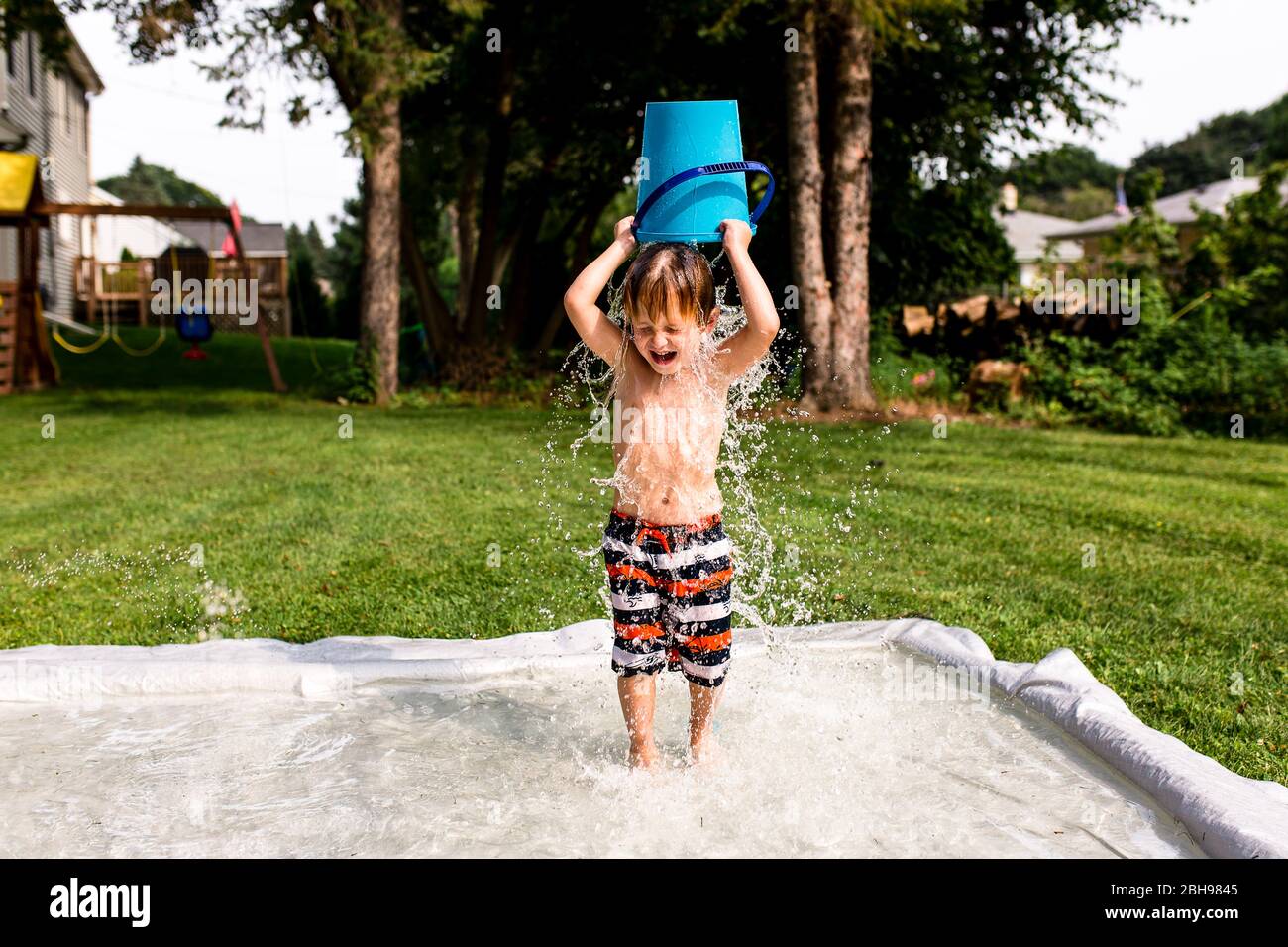 Young Boy Pouring Water Bucket Over Head Stock Photo - Alamy