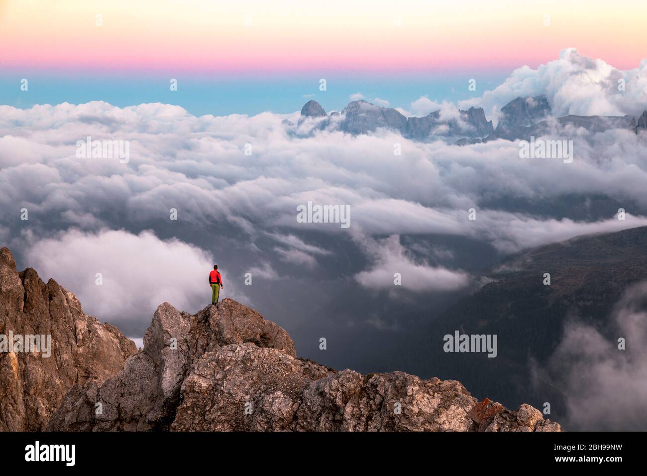 Lonely man stands on top of a mountain ridge, on the background a sea ...