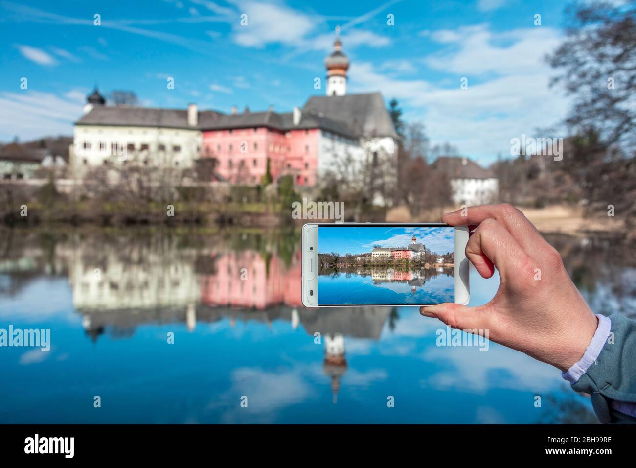 Tourist taking a snapshot with his mobile phone in Höglwörth abbey of ...
