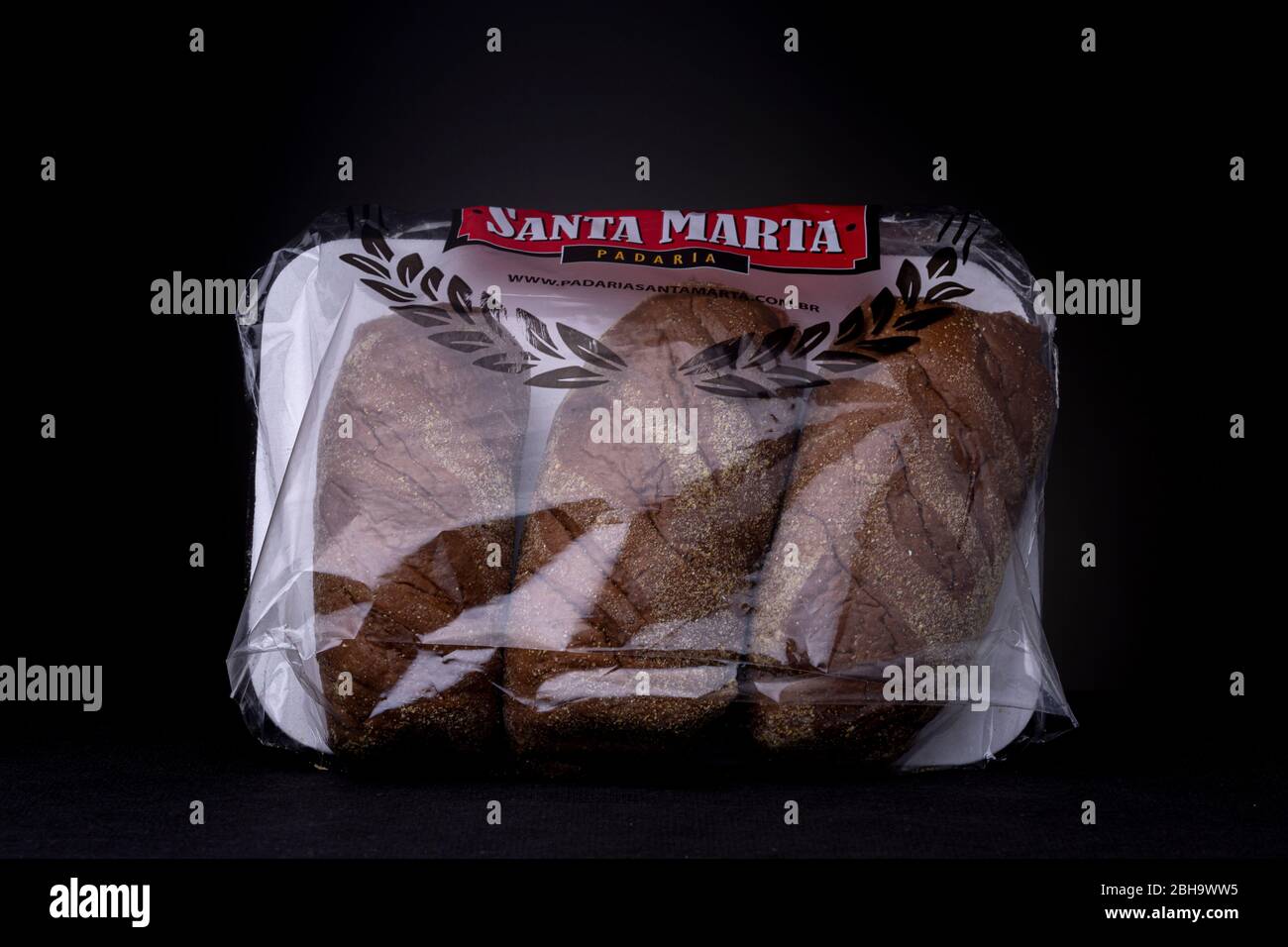 Fresh cereal bread in plastic wrap on white foam. Studio low key still ...