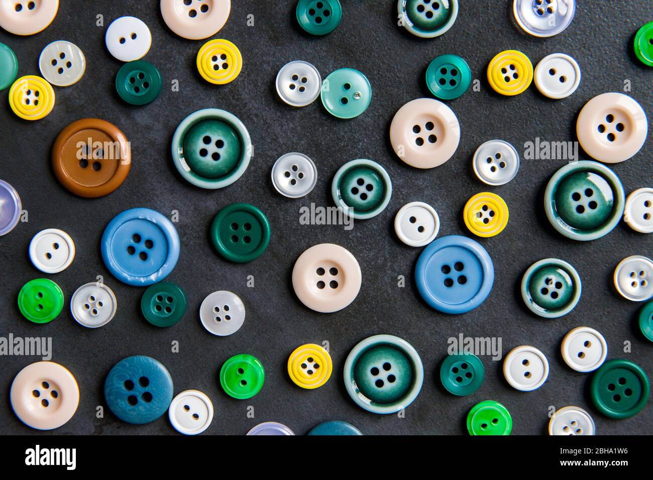 Colorful mixed sewing buttons on black background, flat lay. Top view ...