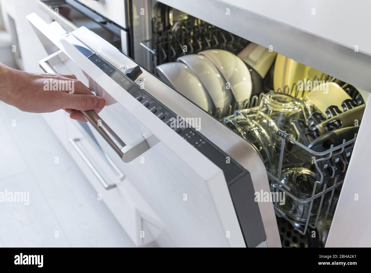 Man hand opens the dishwasher with clean dishes in it after washing ...